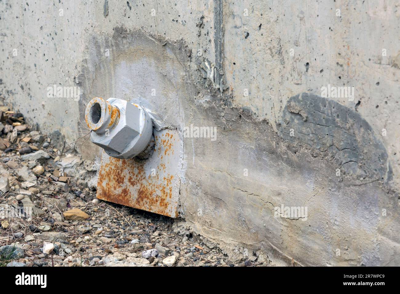 twisted metal nut covered with rust on the concrete wall of the bridge ...