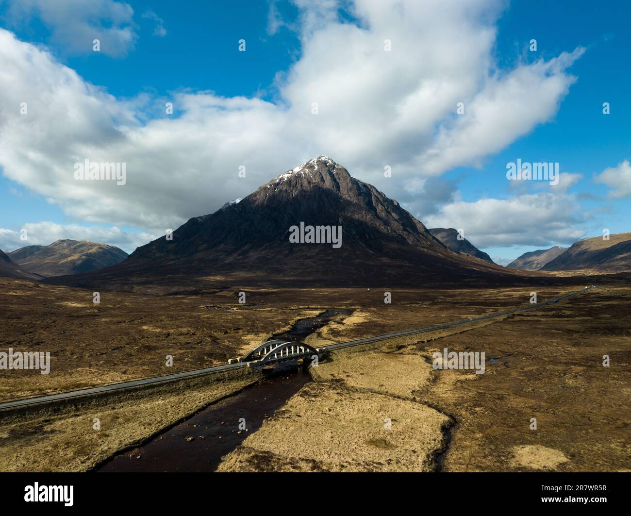 A winding road cuts through a parched desert landscape, with dramatic ...