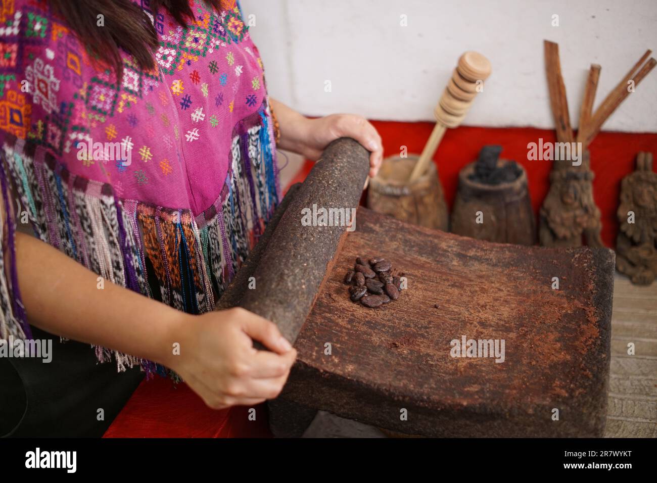 Guatemalan mayan woman making chocolate with traditional grinding stone ...