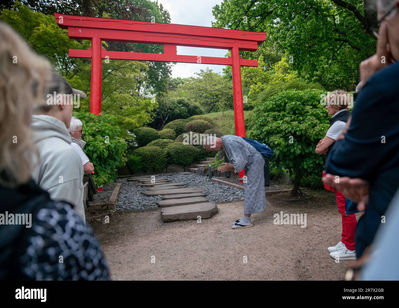 05-13-2023 Kaiserlautern , Germany. Guide bowing in Japanese garden in ...