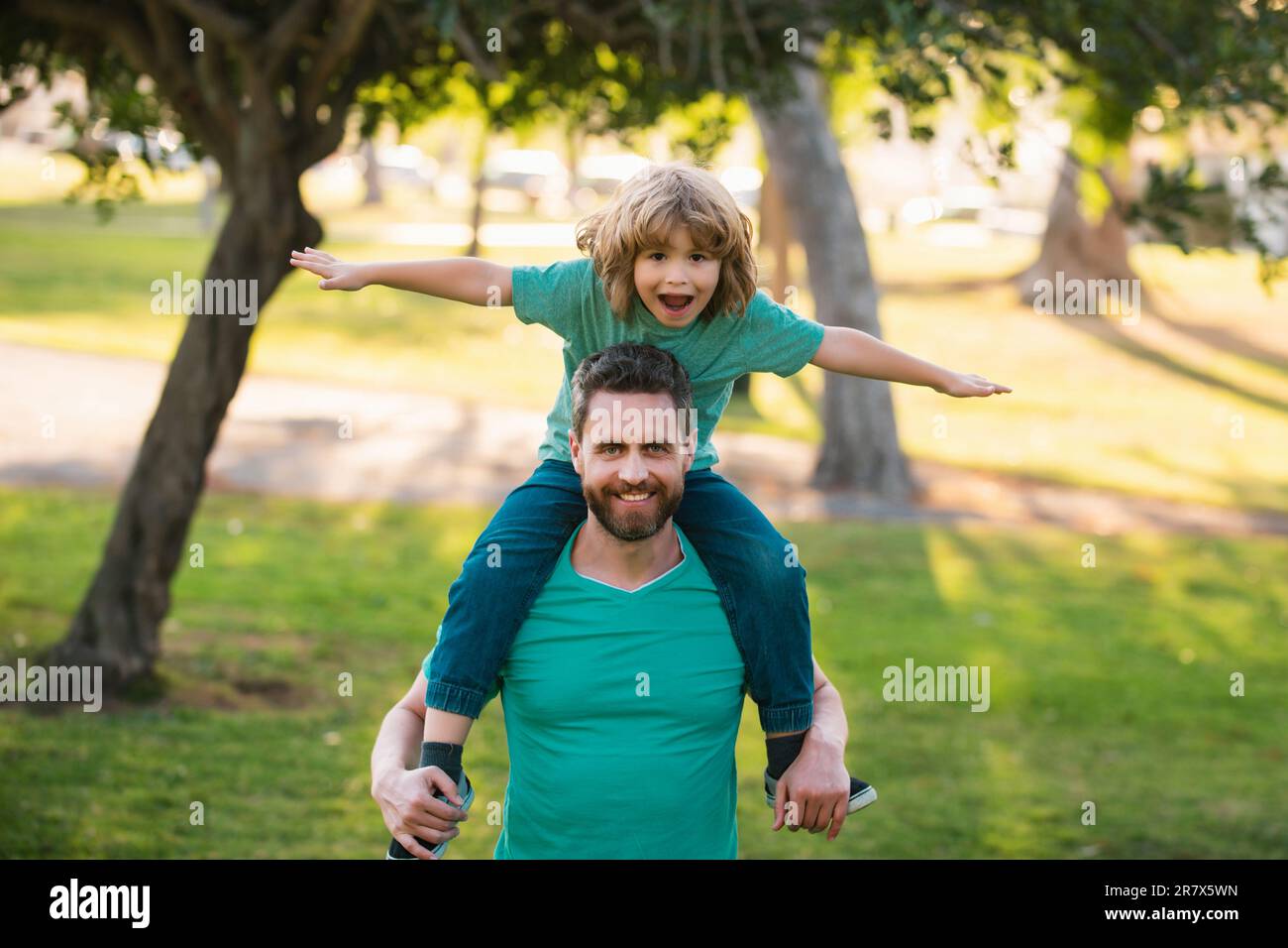 Happy father giving shoulder ride on his shoulders in garden. Son on ...
