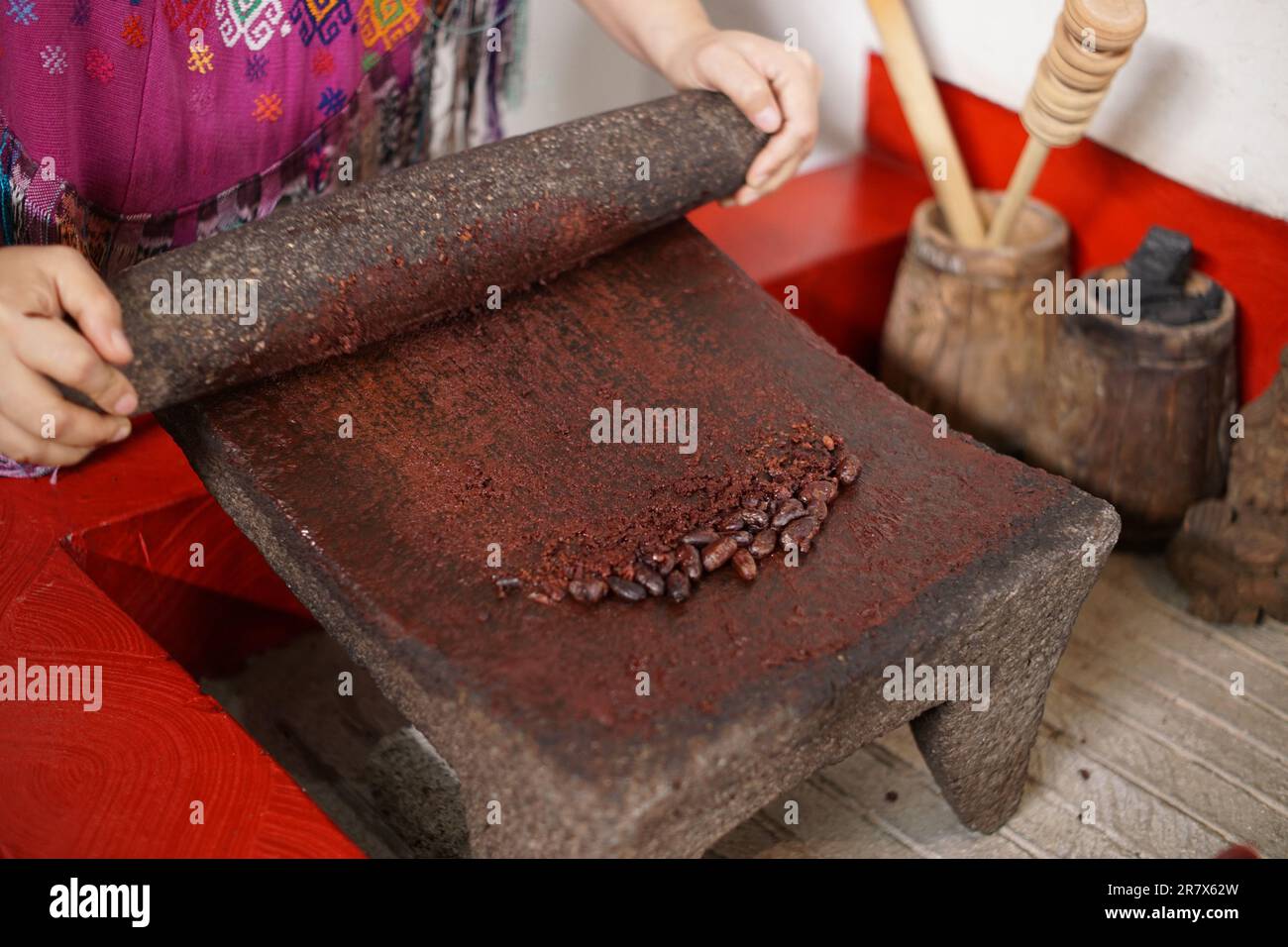 Guatemalan mayan woman making chocolate with traditional grinding stone ...
