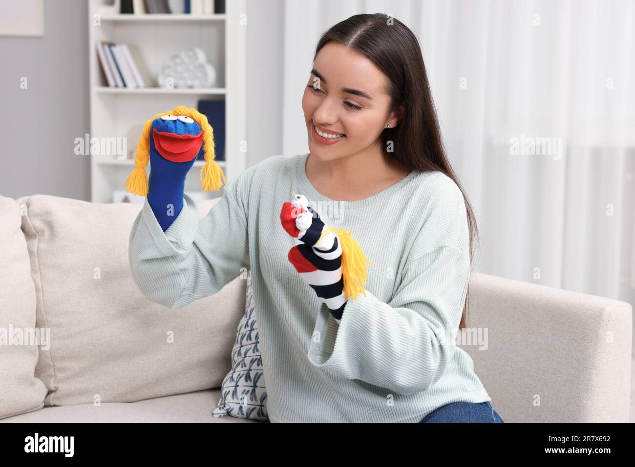 Happy woman performing puppet show on sofa at home Stock Photo - Alamy