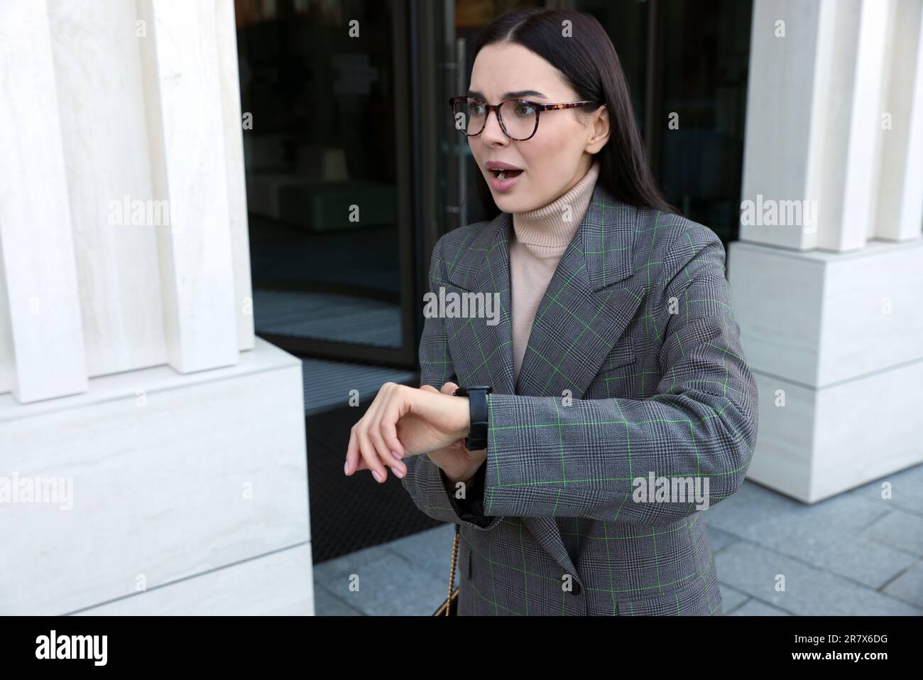 Emotional woman checking time on watch outdoors. Being late concept ...