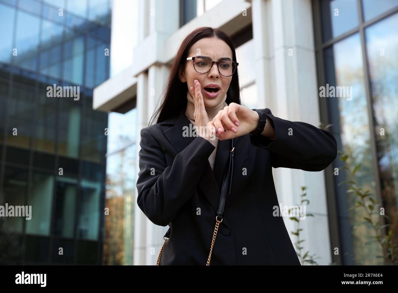 Emotional woman checking time on watch outdoors. Being late concept ...