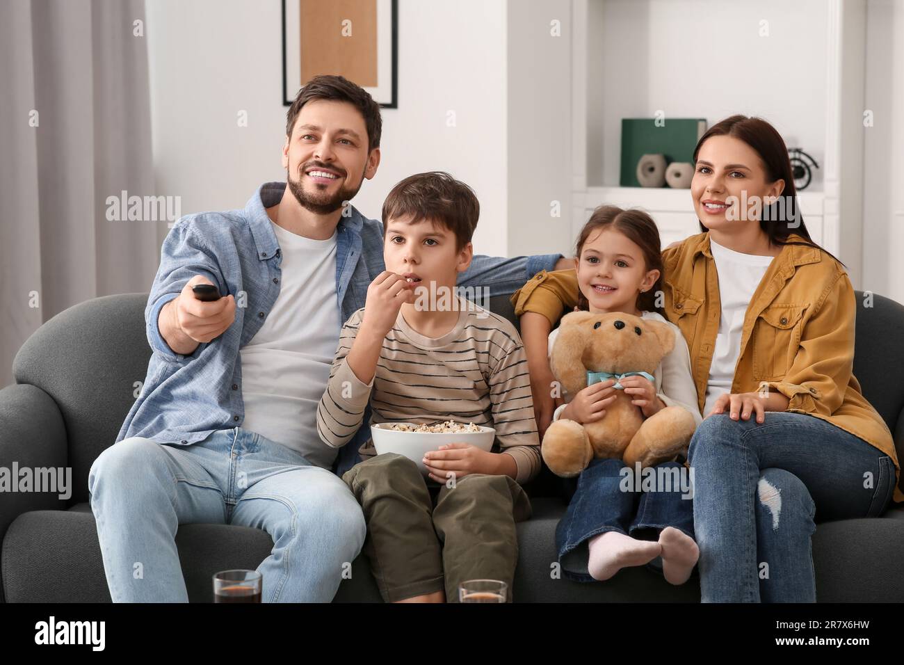 Happy family watching TV at home. Father changing channels with remote ...