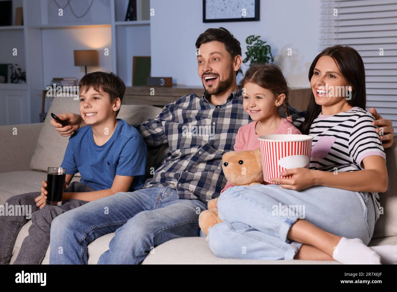 Happy family watching movie at home in evening. Father changing TV ...