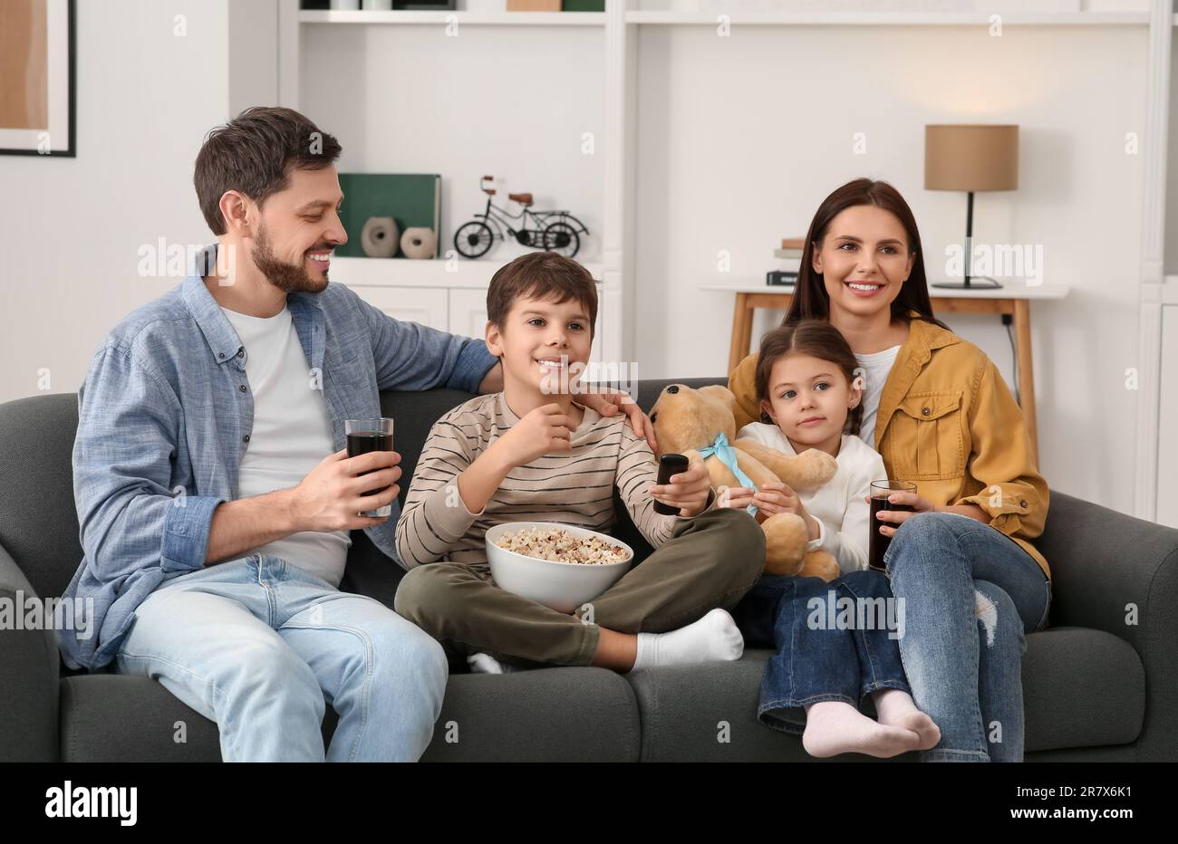 Family spending time together on sofa at home. Son changing TV channels ...