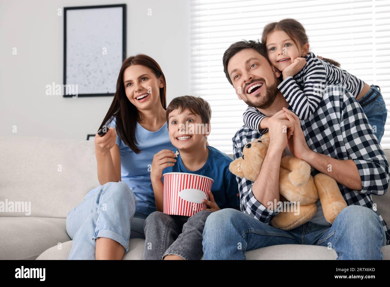 Happy family watching movie at home. Mother changing TV channels with ...