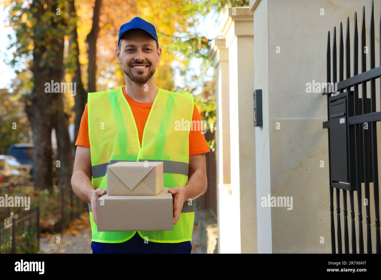 Courier in uniform with two parcels outdoors Stock Photo - Alamy