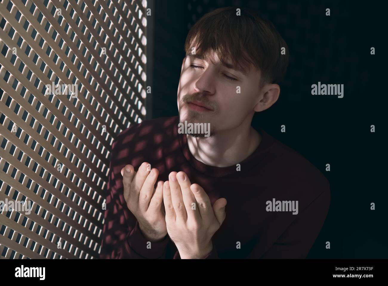 Man praying during confession near wooden window in booth Stock Photo ...