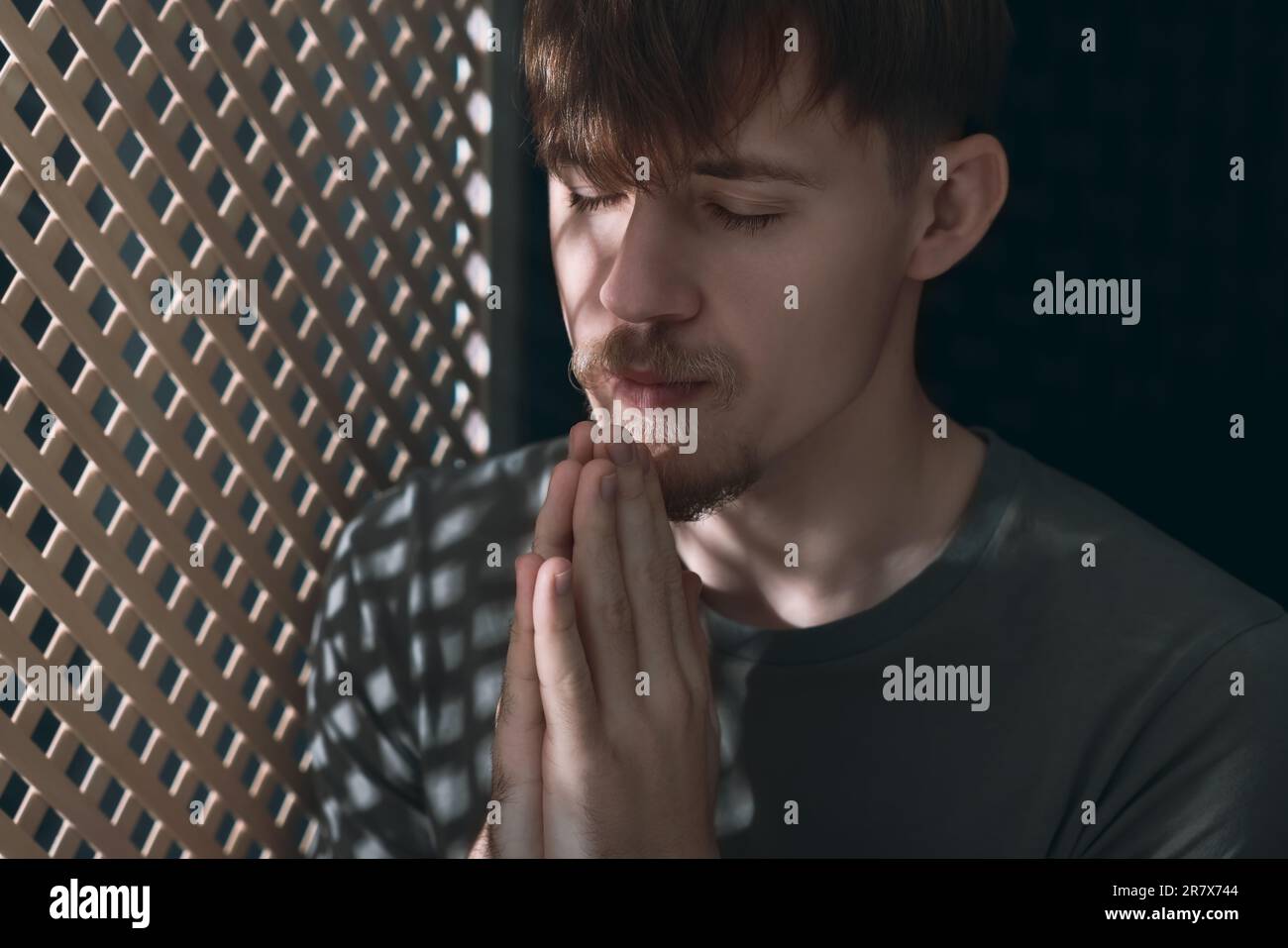 Man praying during confession near wooden window in booth Stock Photo ...