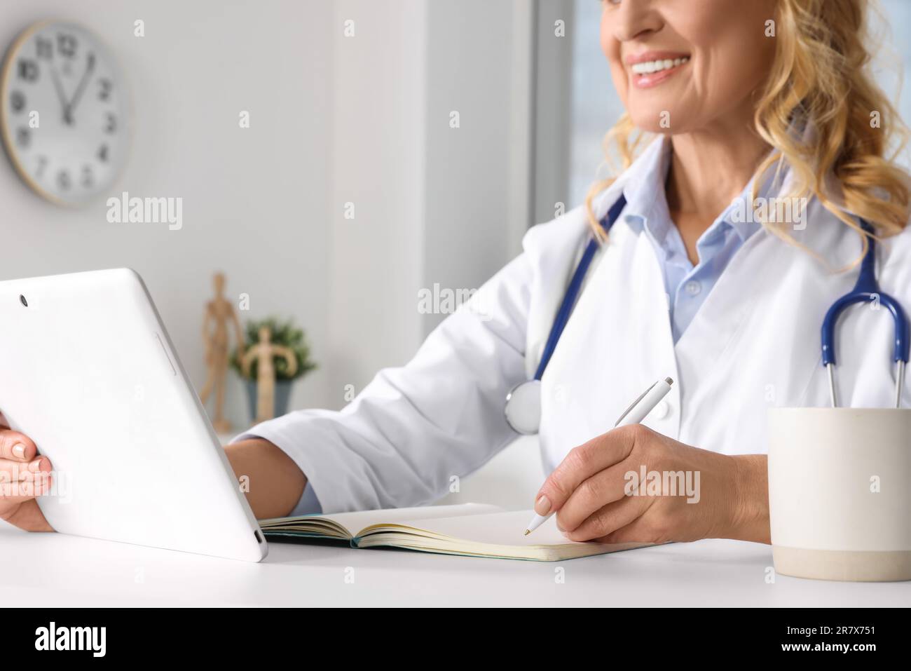 Doctor with tablet and notebook at desk in clinic, closeup. Online ...