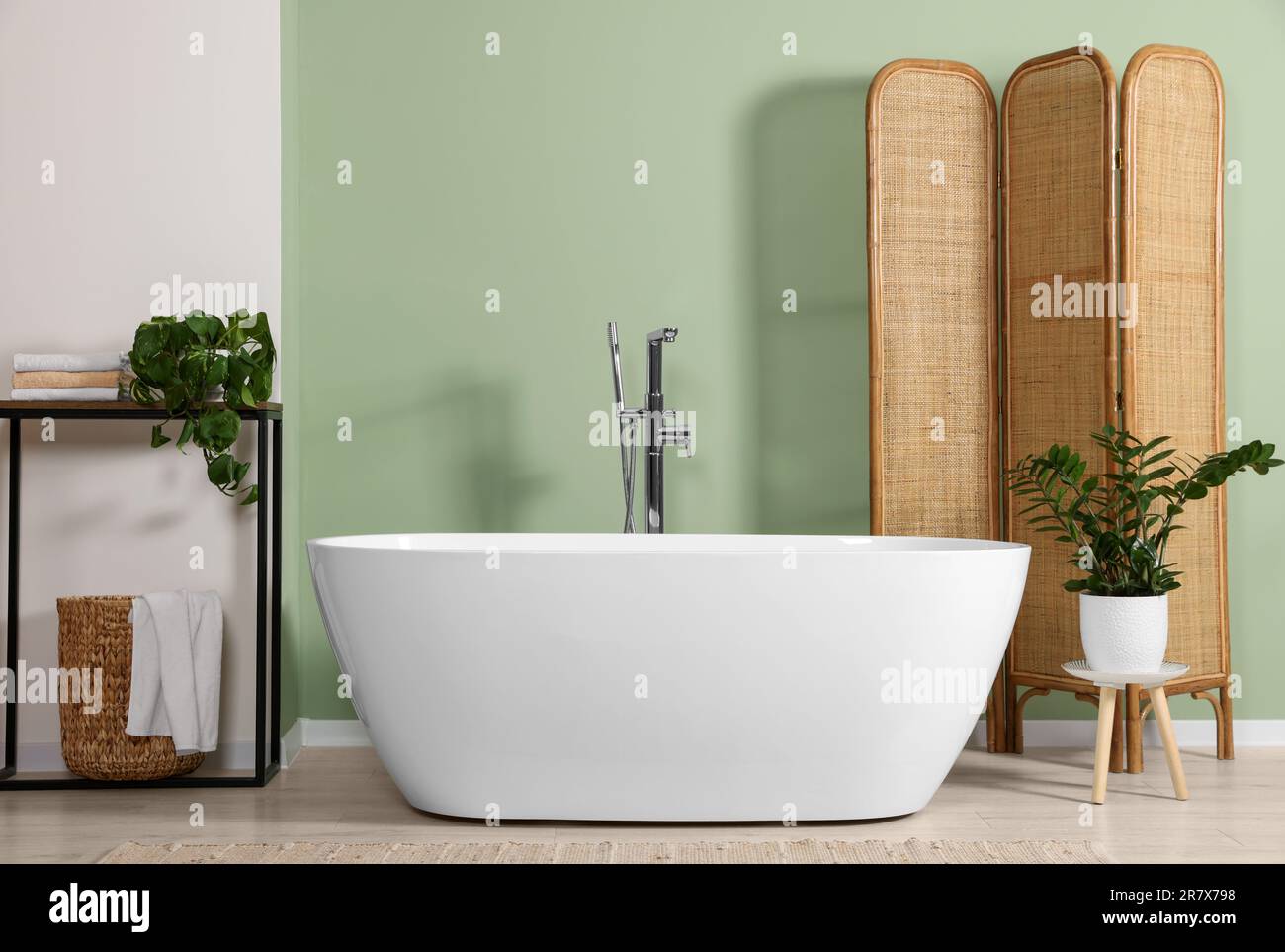 Modern ceramic tub and beautiful plants near light green wall in ...