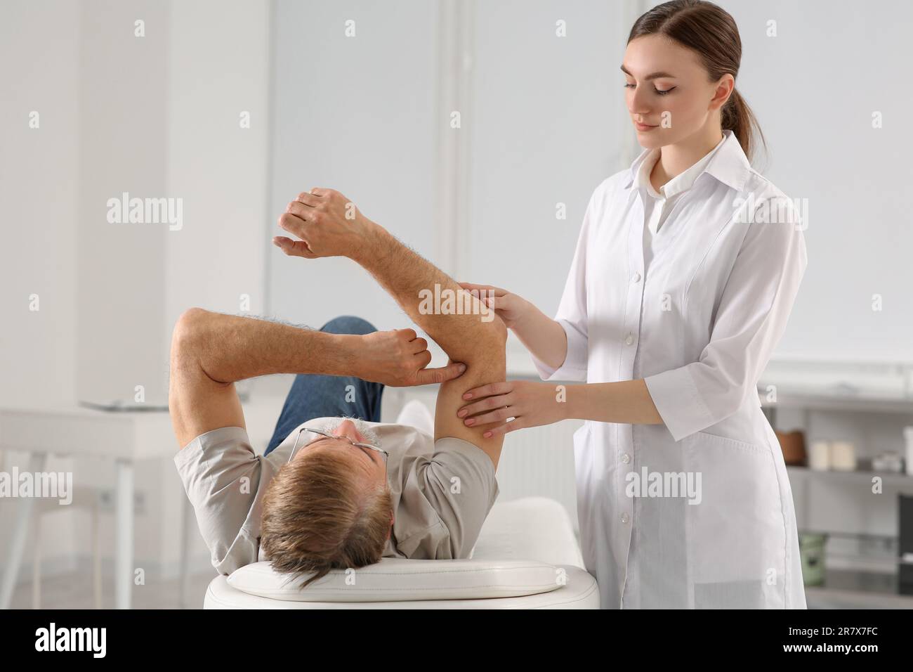 Professional orthopedist examining patient's arm in clinic Stock Photo ...