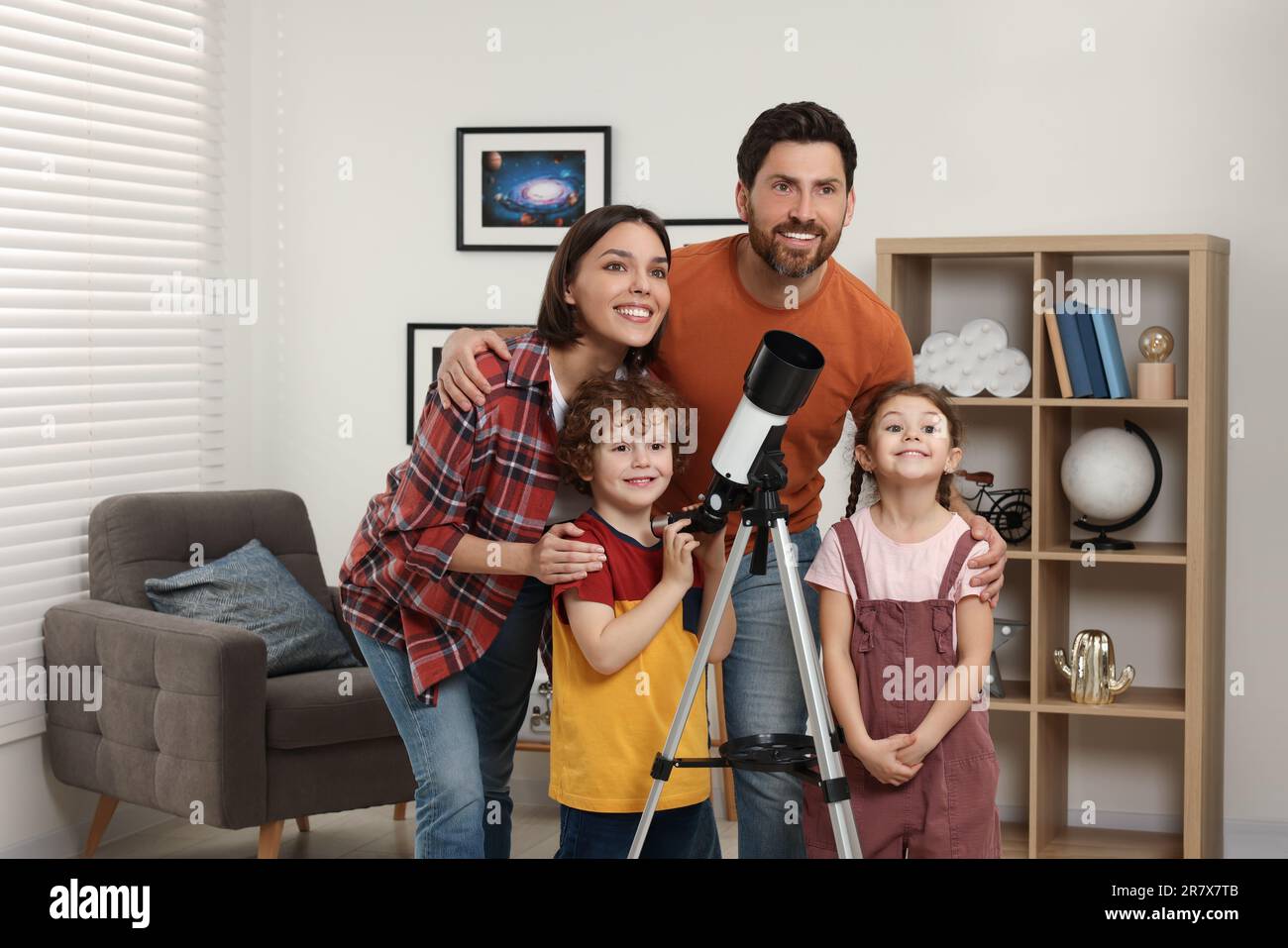 Happy family looking at stars through telescope in room Stock Photo - Alamy