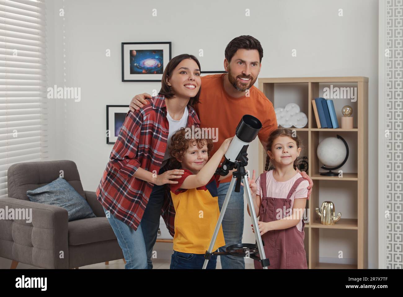 Happy family looking at stars through telescope in room Stock Photo - Alamy