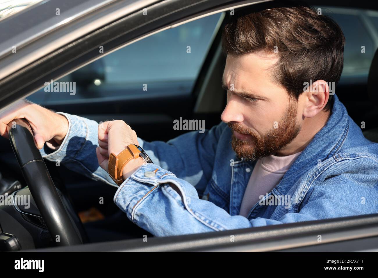 Emotional man checking time on watch in car. Being late concept Stock ...