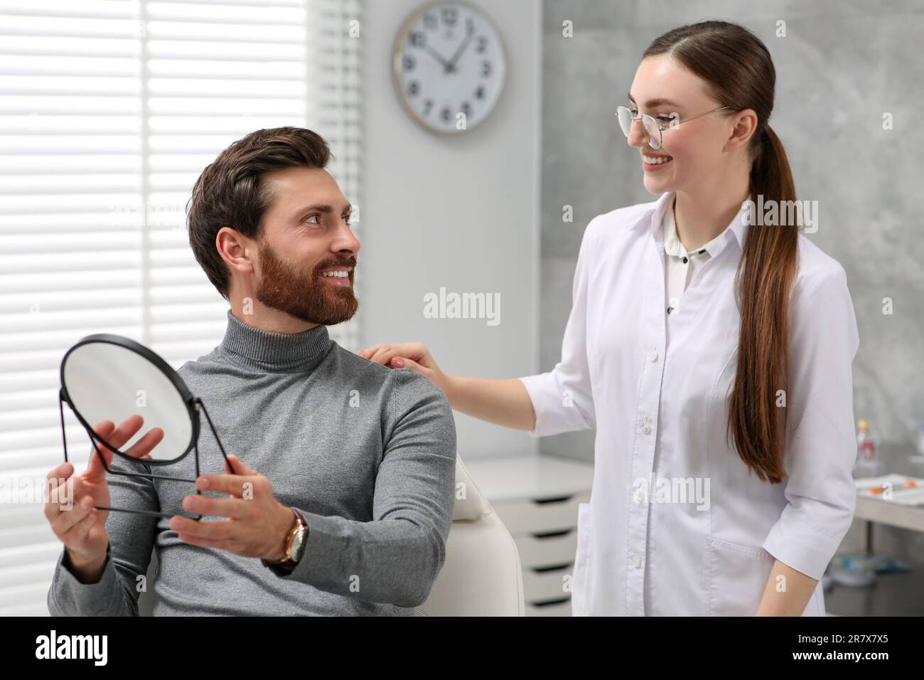 Dentist and patient with mirror in clinic. Dental implants installation ...