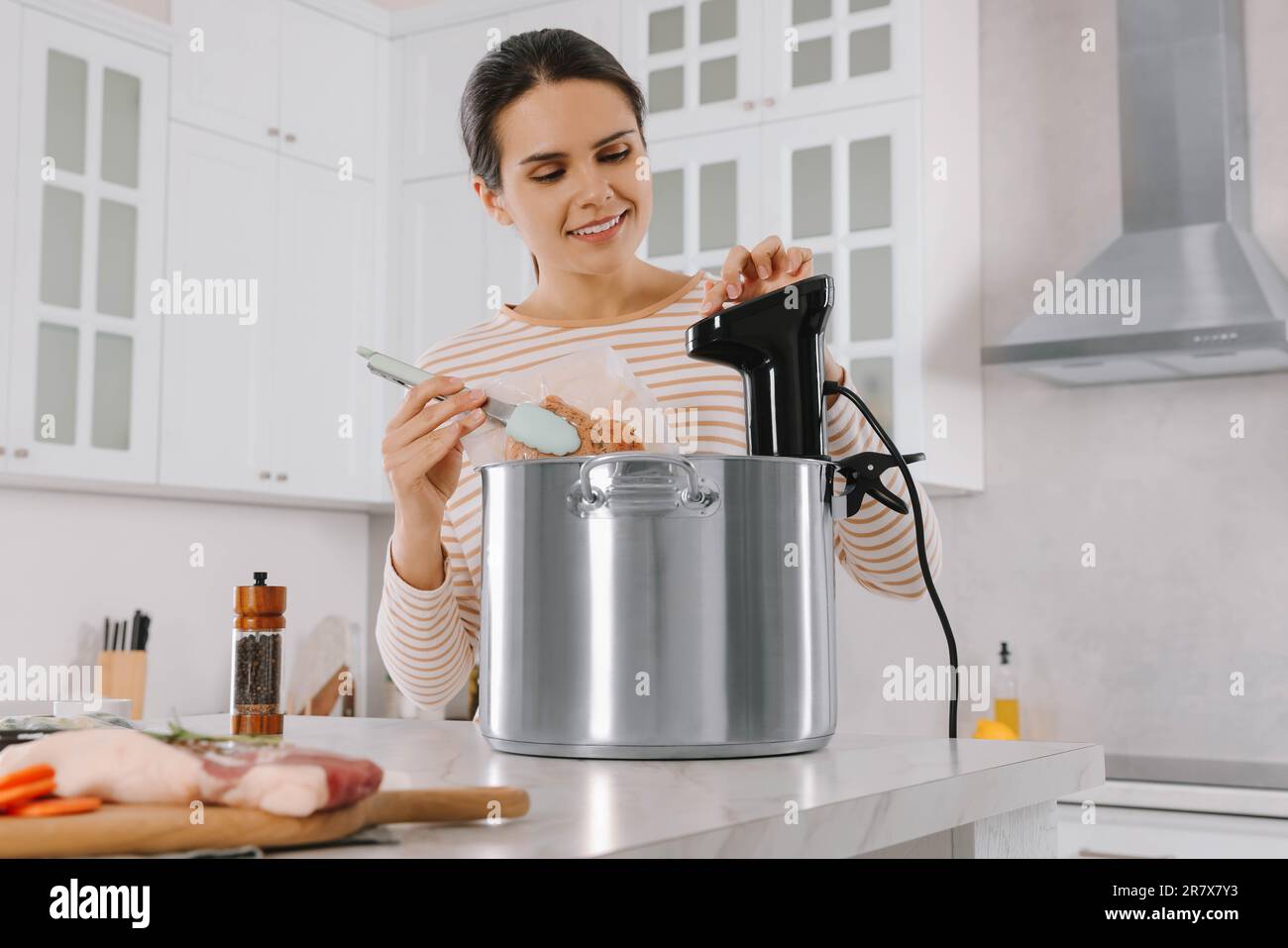 Woman putting vacuum packed meat into pot and using thermal immersion ...