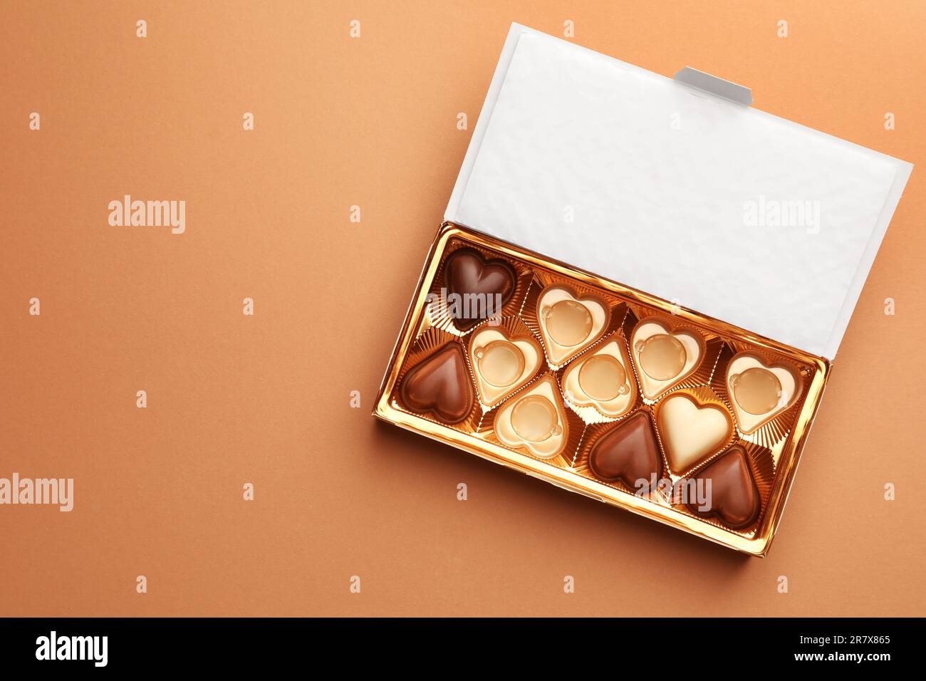 Partially empty box of chocolate candies on light brown background, top ...