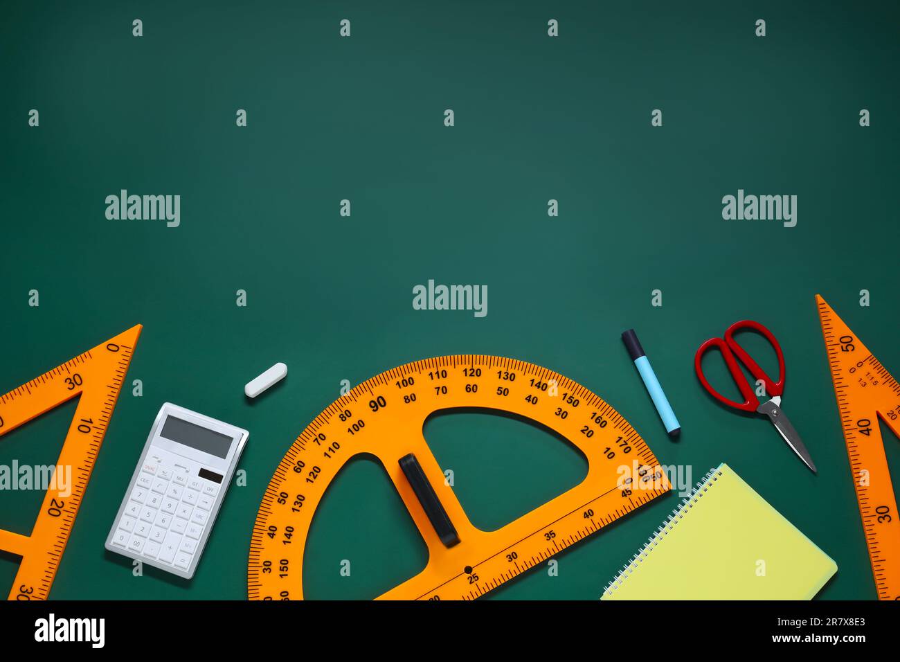 Flat lay composition with protractor, triangle and stationery on green ...