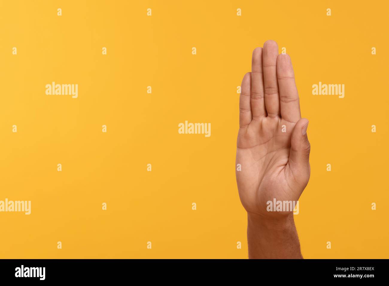 Man giving high five on yellow background, closeup of hand. Space for ...