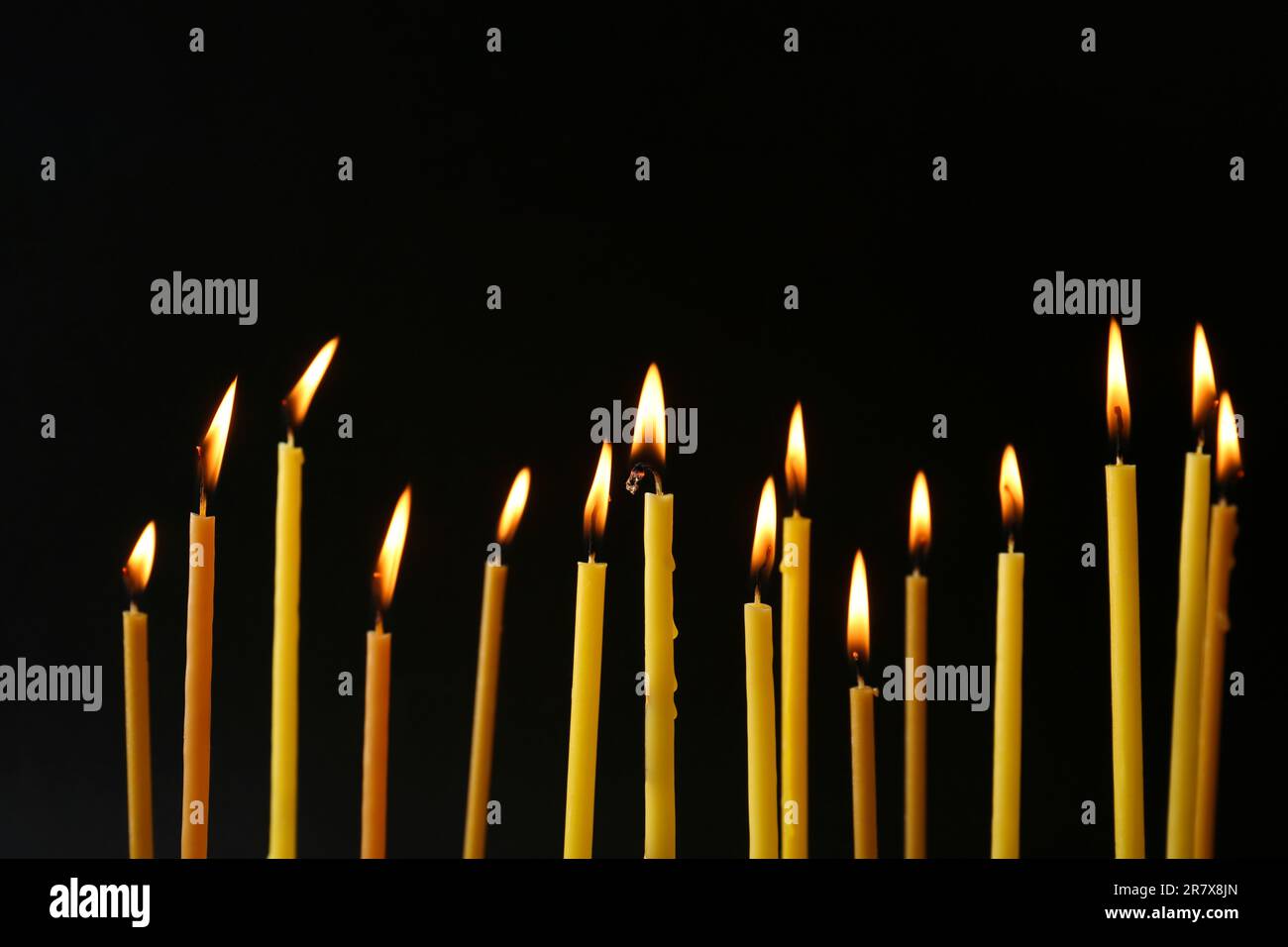 Many burning church candles on black background Stock Photo - Alamy