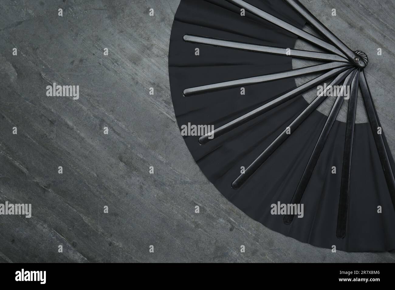 Stylish black hand fan on grey background, top view. Space for text ...