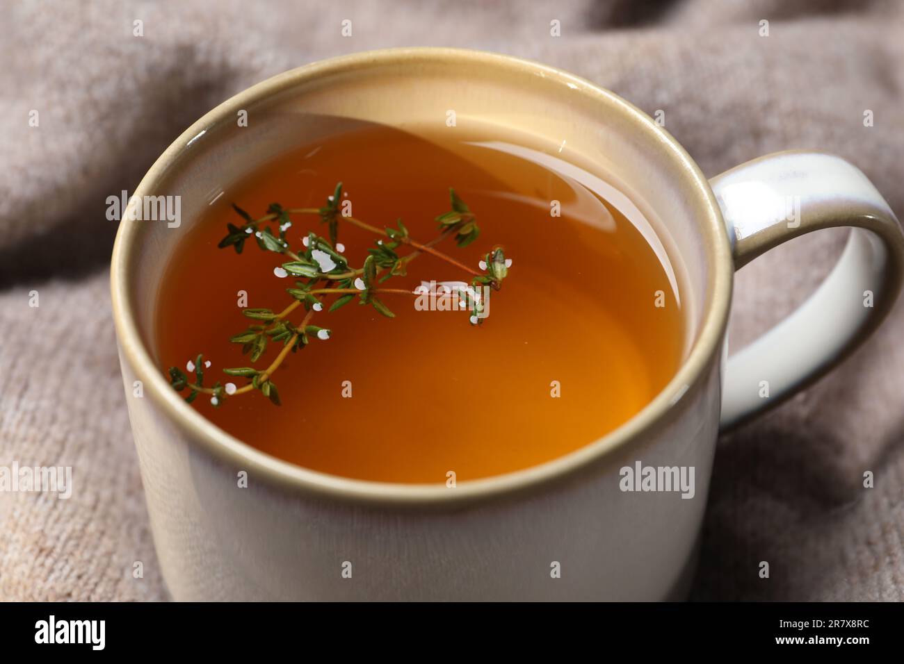 Cup of aromatic herbal tea with thyme on beige fabric, closeup Stock ...