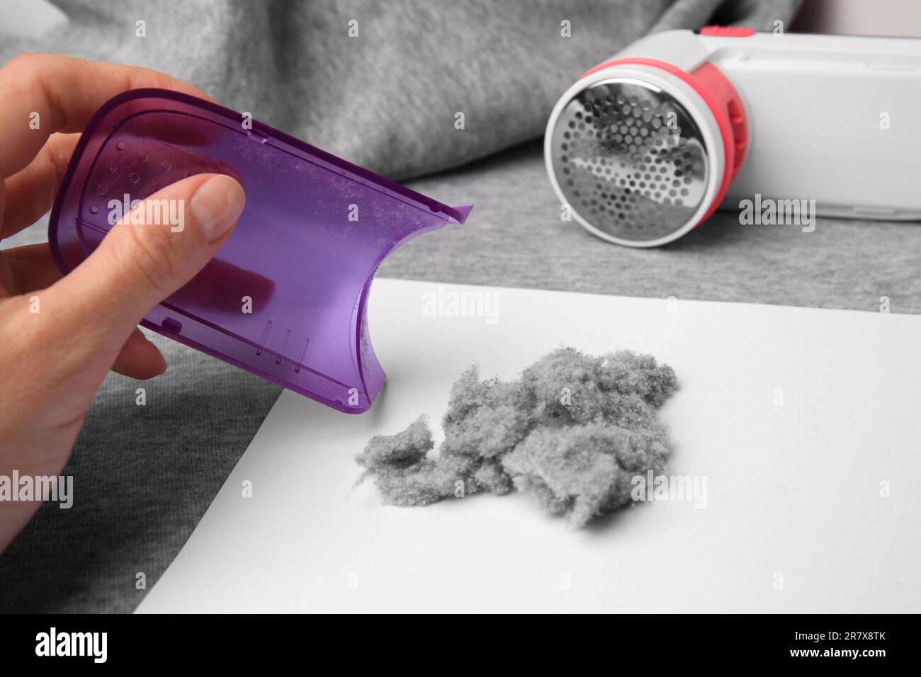 Woman holding fluff collector of fabric shaver and lint on light grey ...