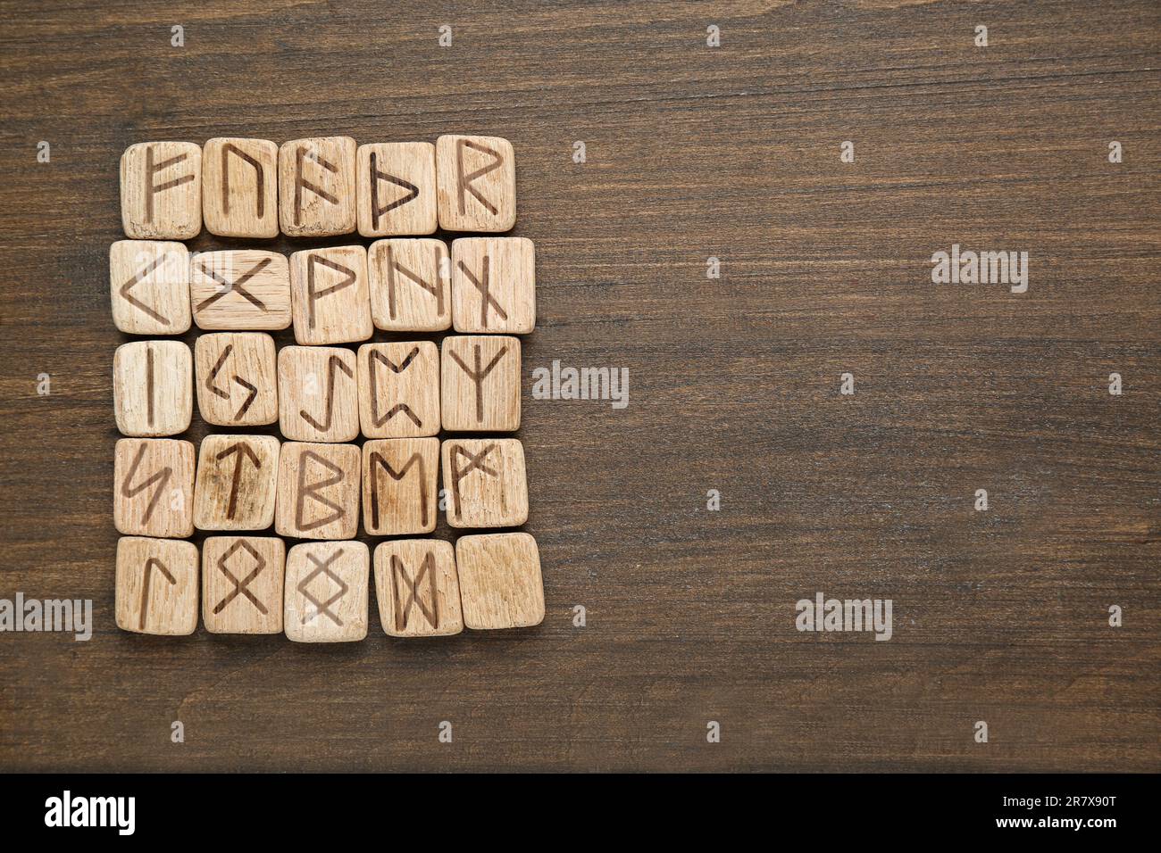 Runes with different symbols on wooden table, top view. Space for text ...