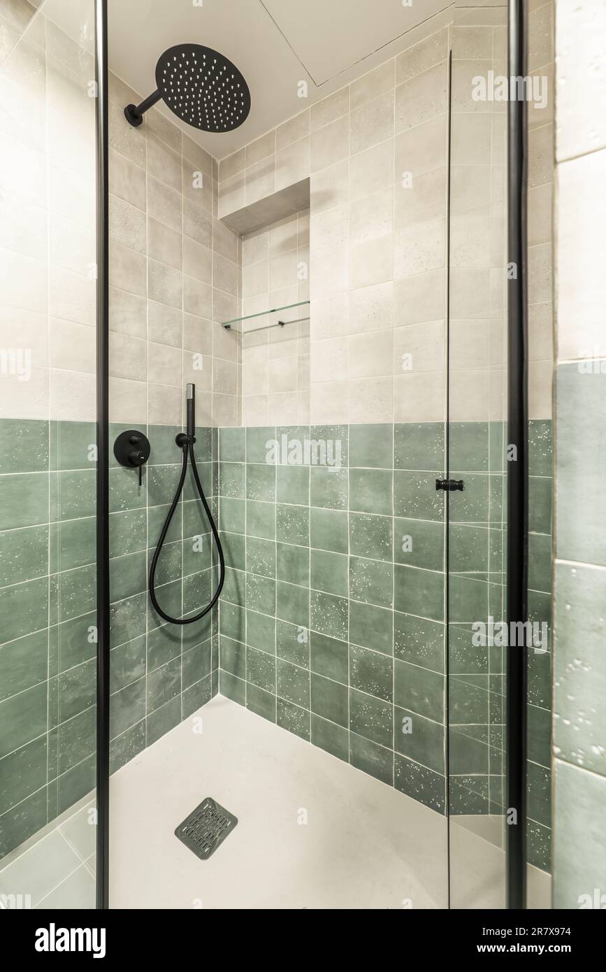 Shower cubicle with green and cream colored tiles, screens with black ...