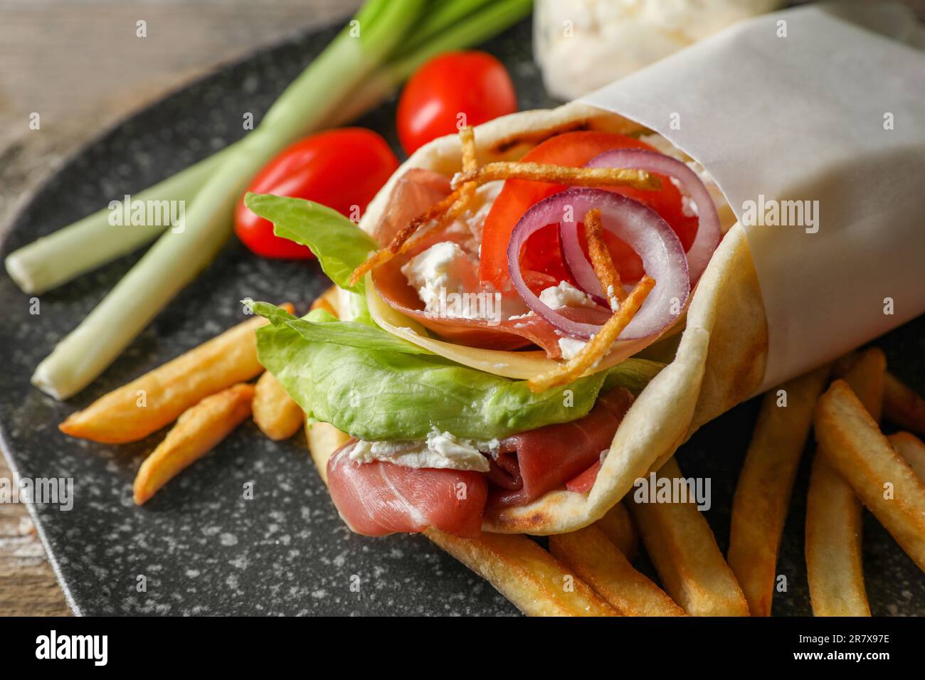 Delicious pita wrap with prosciutto, vegetables and potato fries on ...