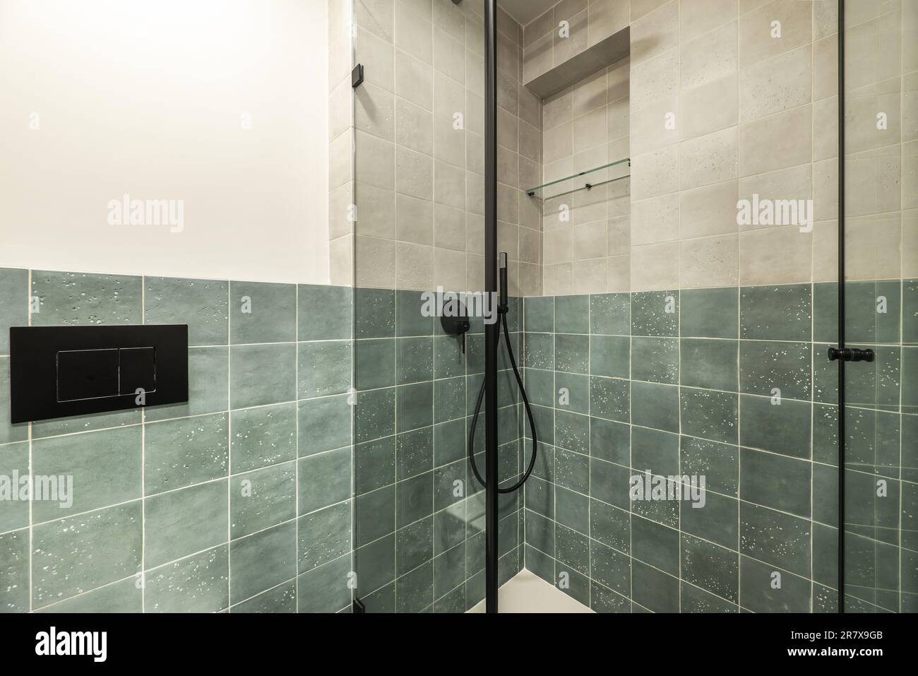 Spacious shower with green and cream tiles, black trim partitions ...