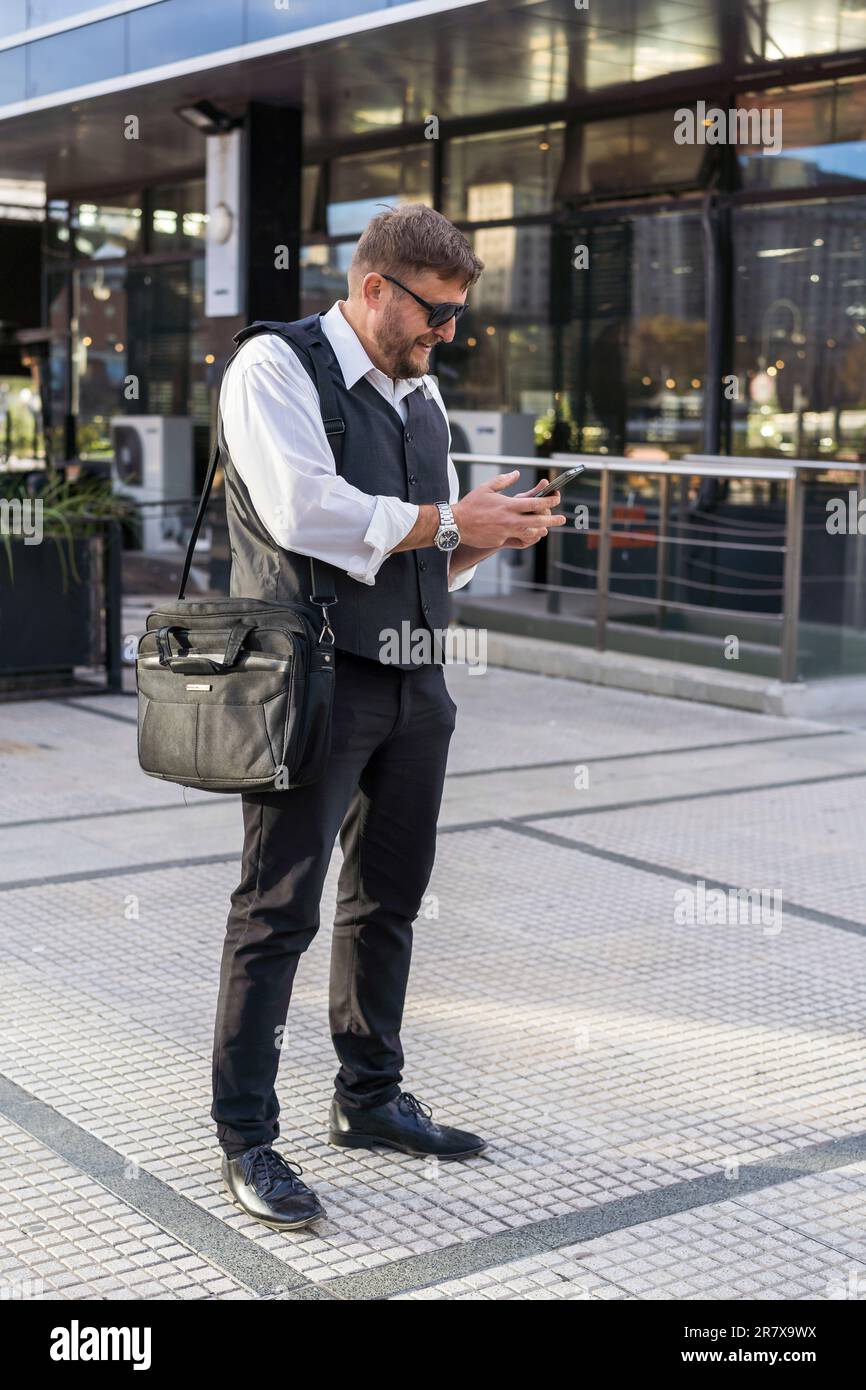 A businessman sendng a message to his friend before entering an after ...