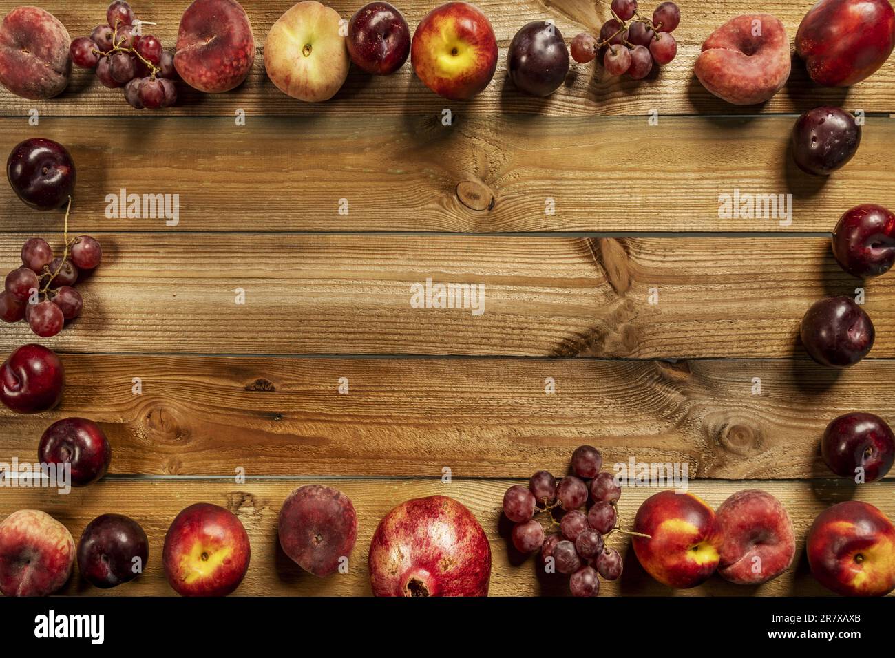 Still life with lots of ripe red seasonal fruit on some unvarnished ...