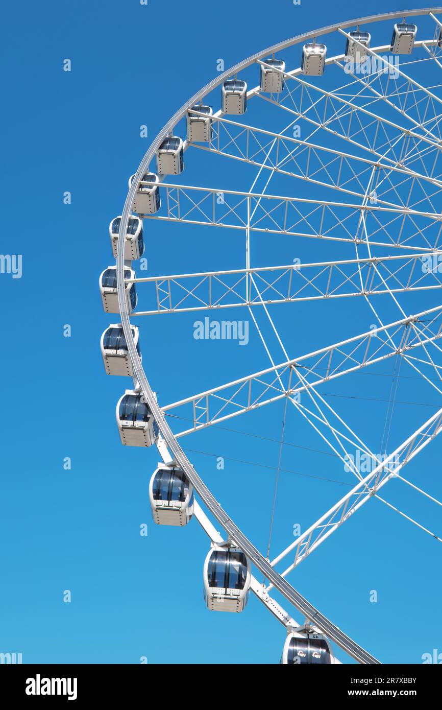 Spokes and passenger cars of a large Ferris wheel against a clear sky ...