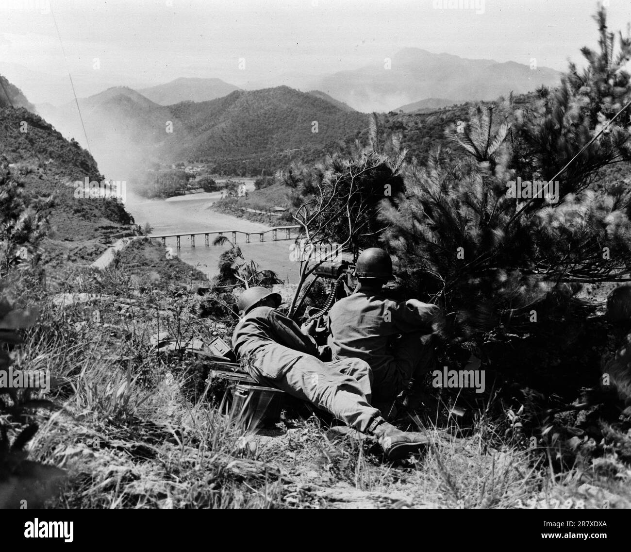US Soldiers manning a heavy machine gun overlooking a valley with a ...