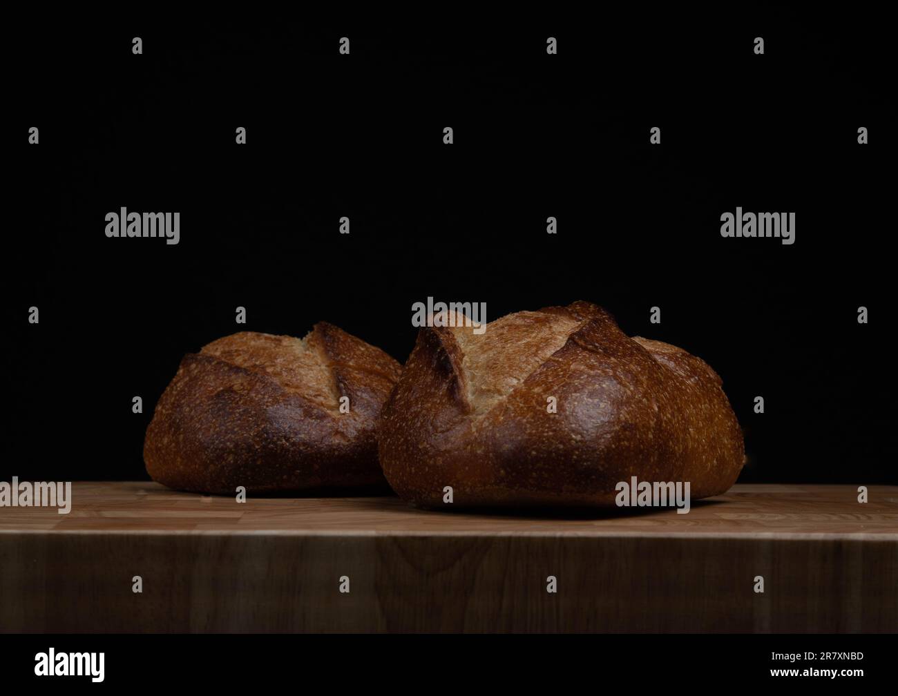 Homemade sourdough crusty loaves of bread on wooden background. Still ...