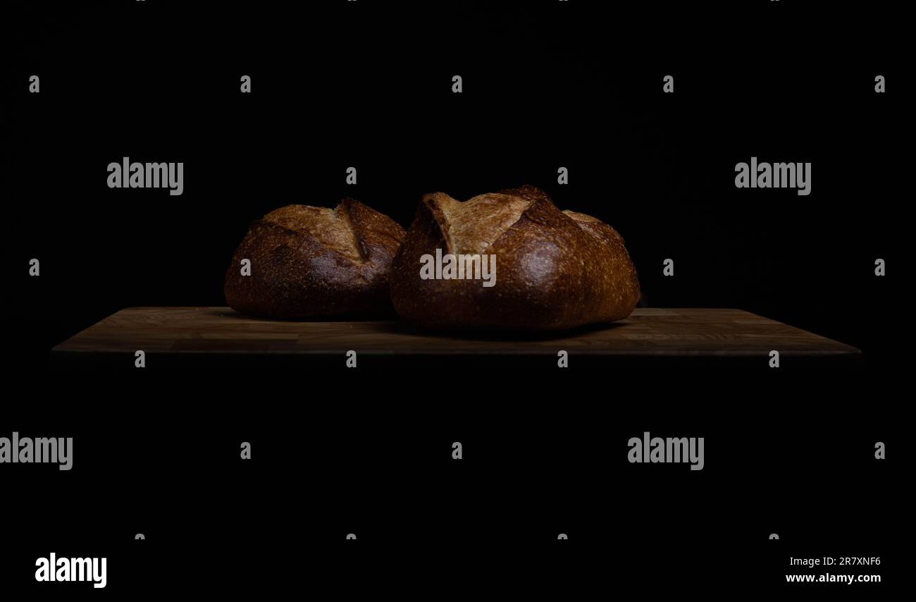 Homemade sourdough crusty loaves of bread on wooden background. Still ...