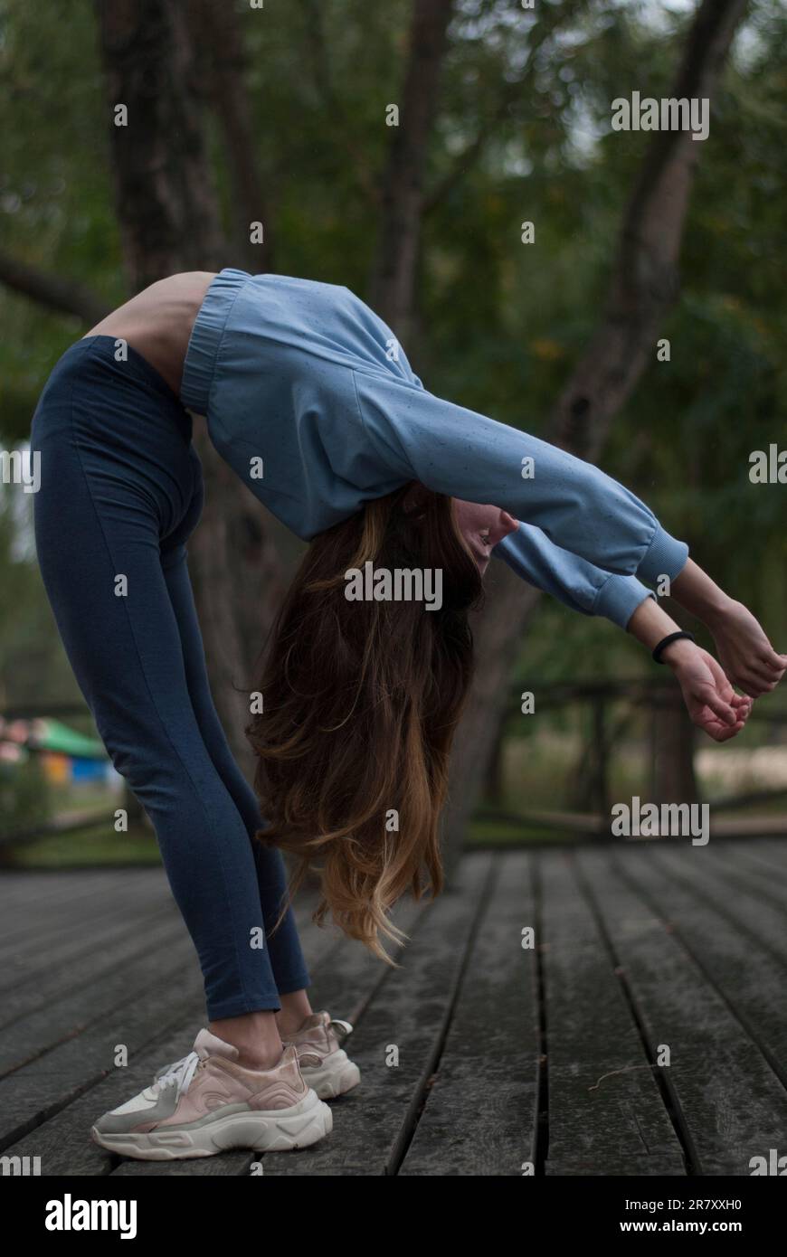 View of a girl with athletic body in blue gym suit is doing exercises ...