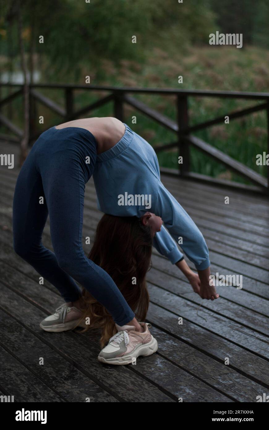 View on young girl in blue gym suit is doing acrobatics exercises in ...