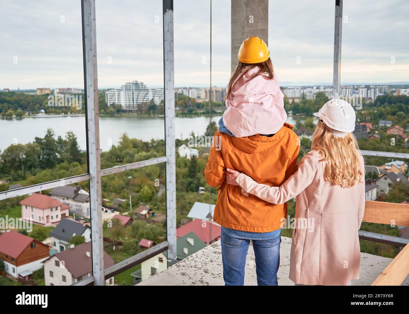 Back view of parents with daughter standing inside apartment building ...