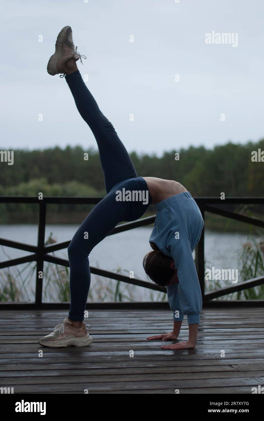 View of a girl with athletic body in blue gym suit is doing acrobatics ...