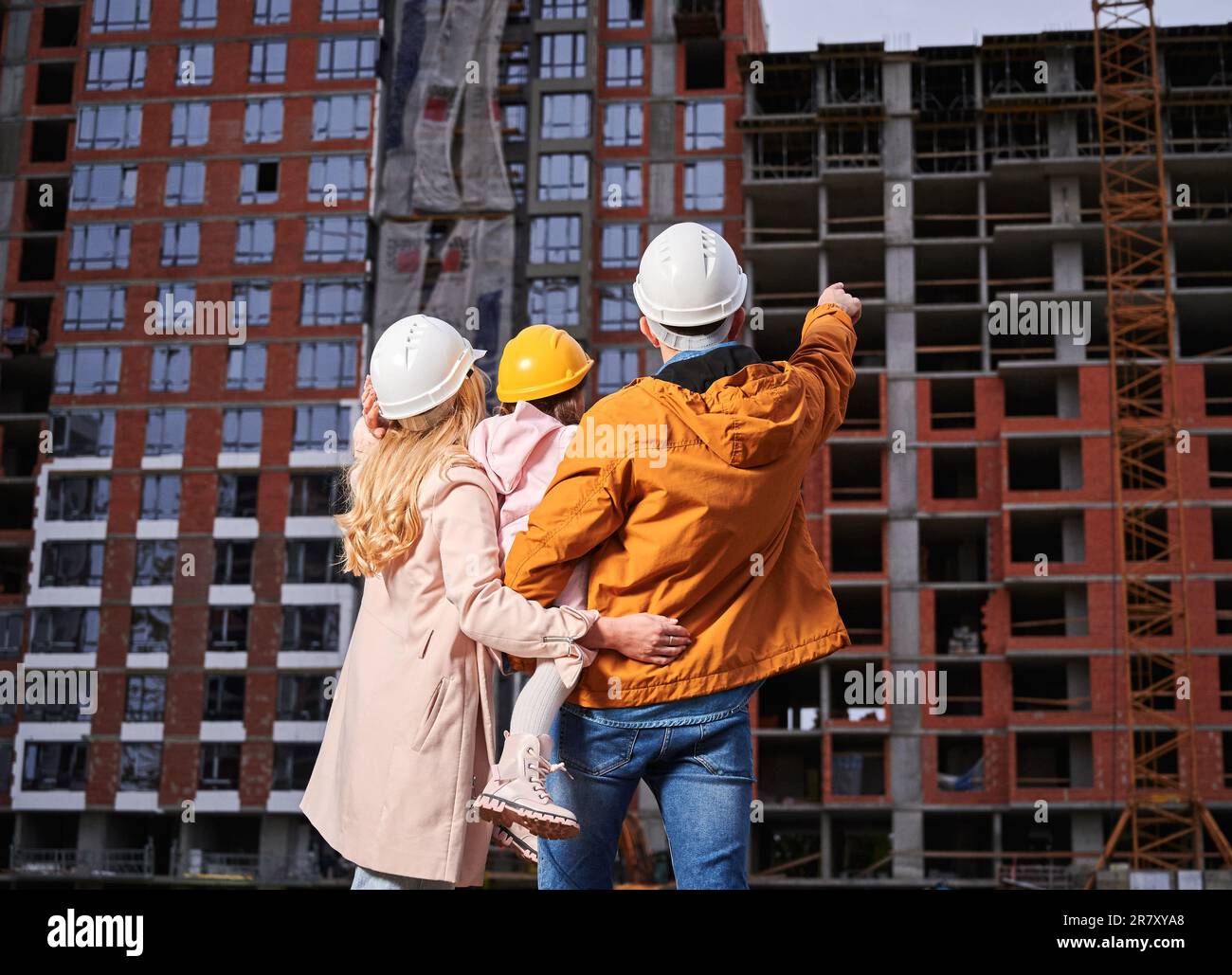 Back view of man pointing at apartment building under constructing ...