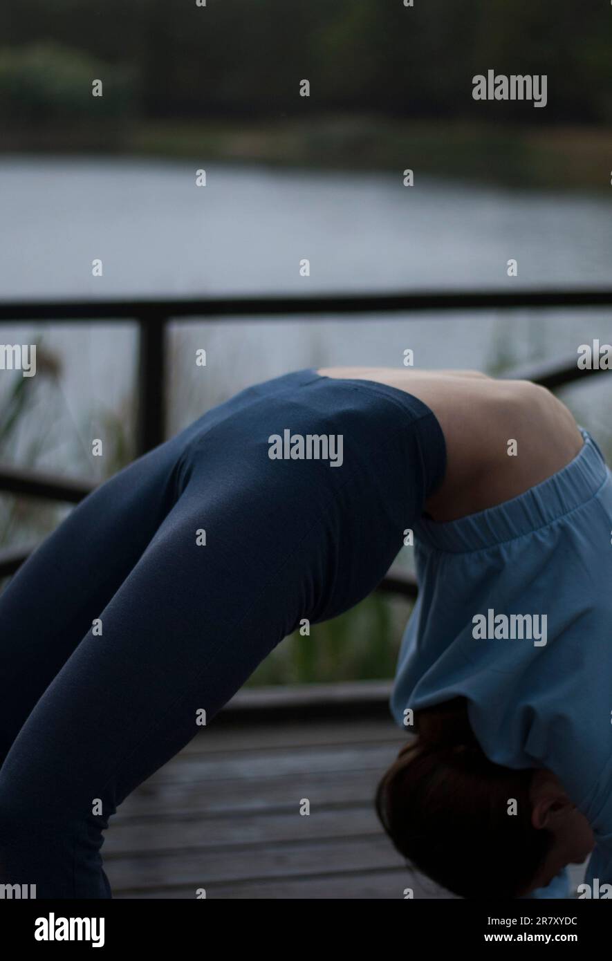 View of a girl with athletic body in blue gym suit is doing acrobatics ...