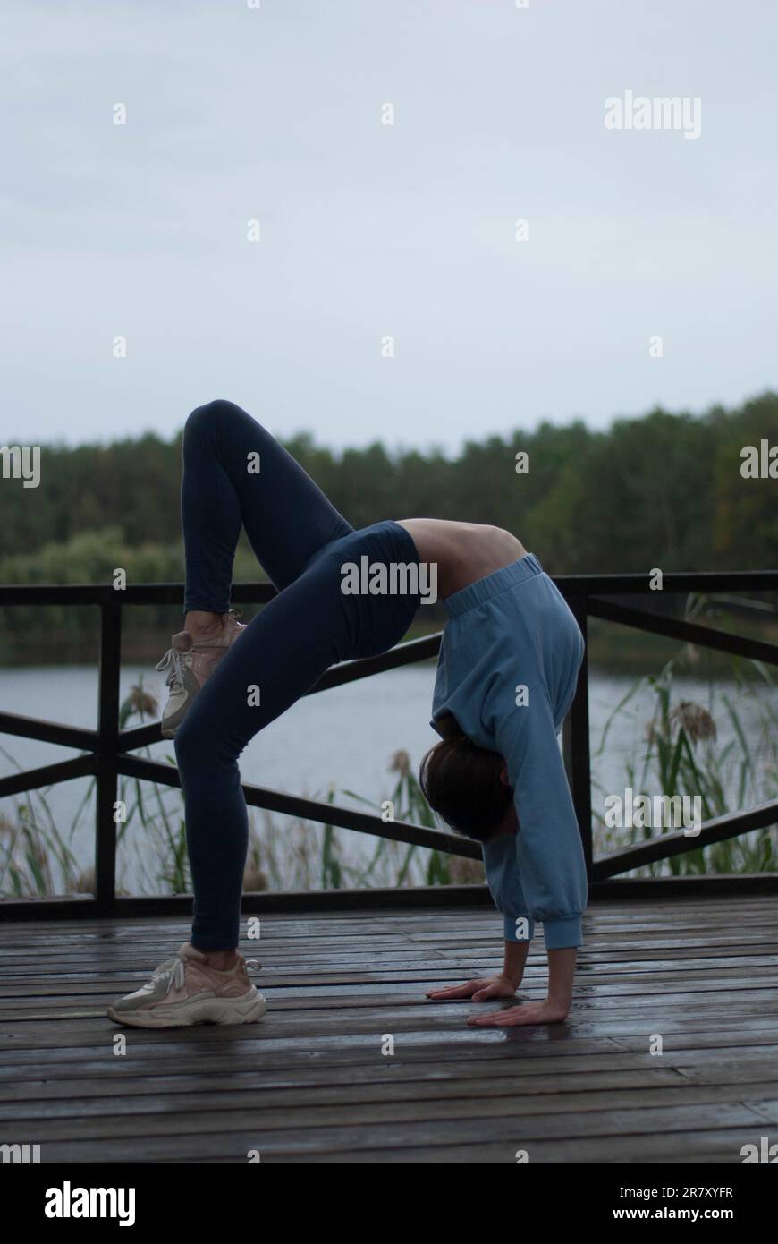 View of a girl with athletic body in blue gym suit is doing acrobatics ...