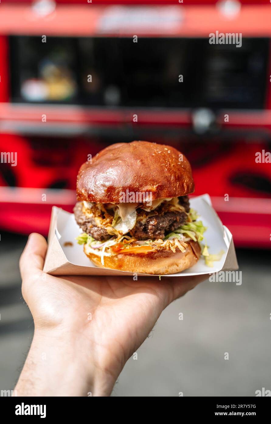 Street food burger on hand on hipster food market background. Grill and ...
