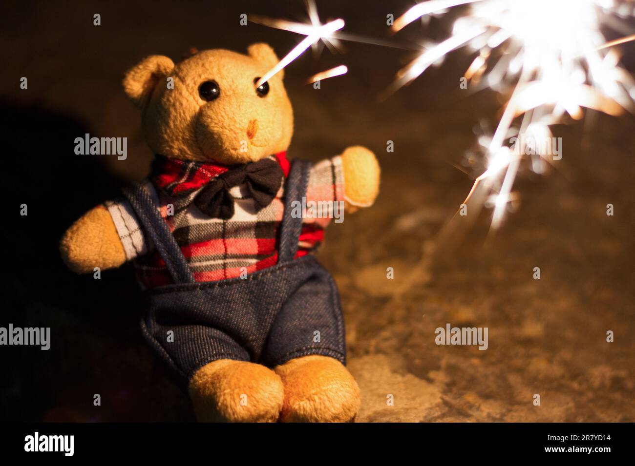 An adorable teddy bear wearing a pair of overalls and a bow tie next to ...